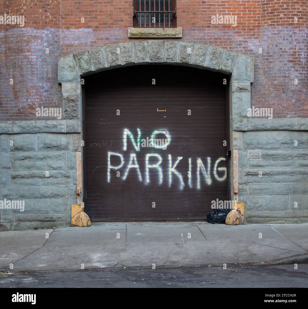 A close-up of a brick building garage door with a no parking spray ...
