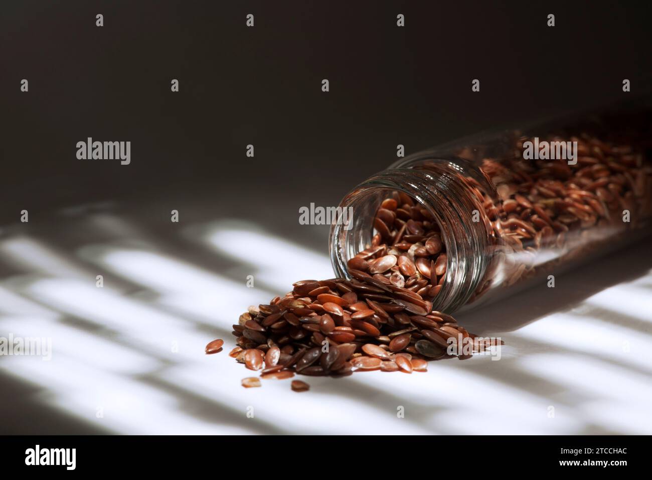 Close-up of a lying open glass tube with linseed grains trickling out ...