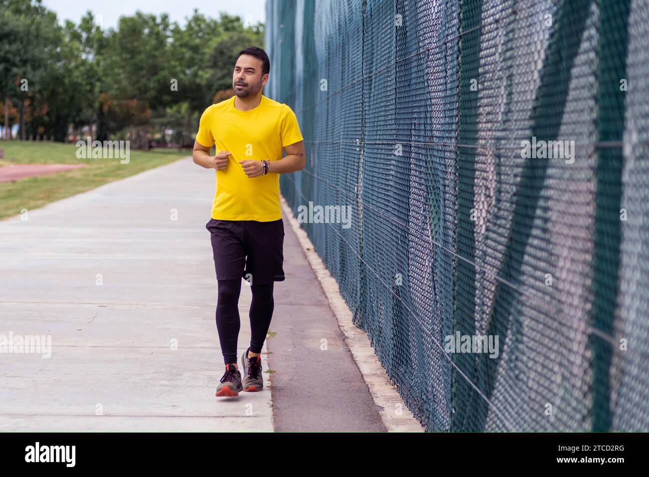 active lifestyle, man jogging along sports ground in an urban park ...