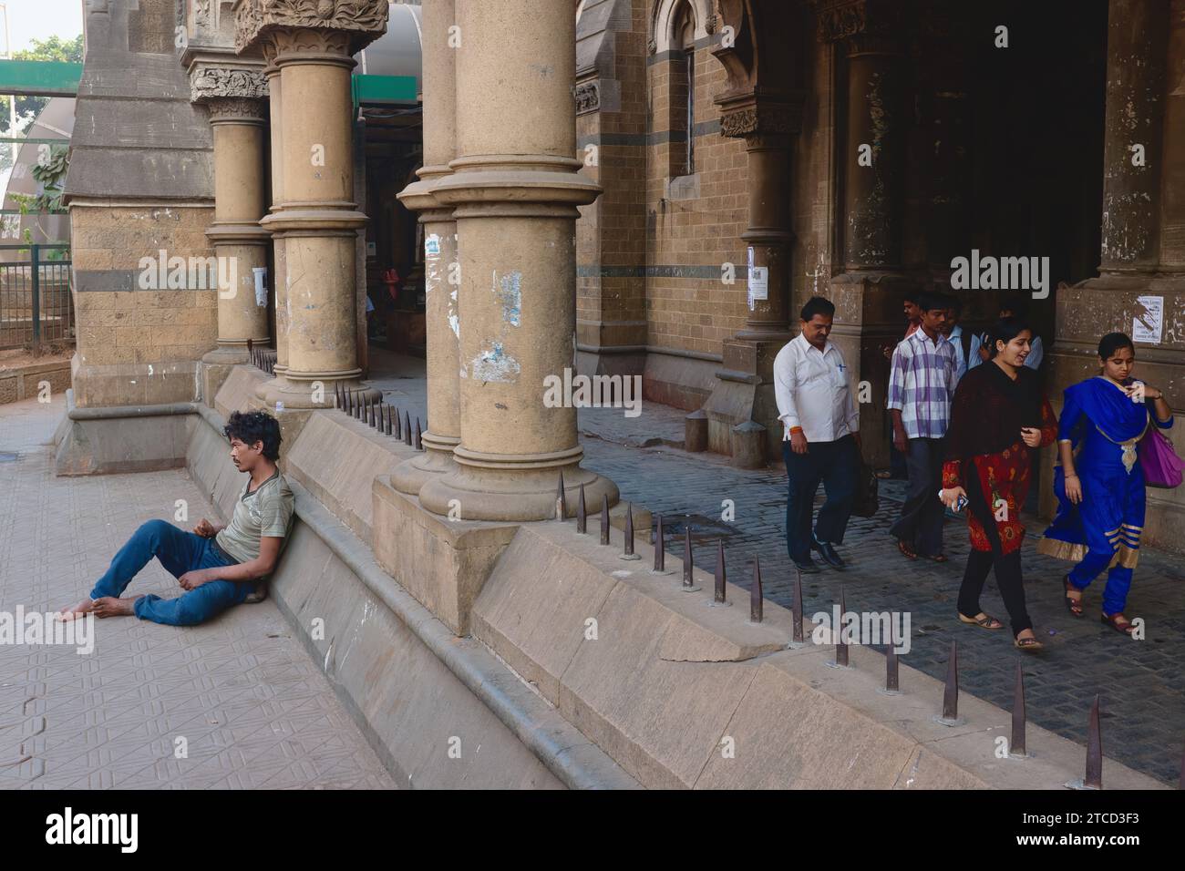 A young, disheveled looking man sits by a wall at Chhatrapati Shivaji ...