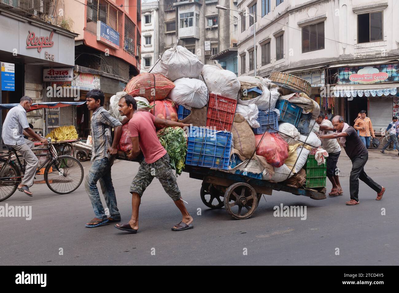 Four men pushing and pulling a heavily laden hand cart along Kalbadevi ...