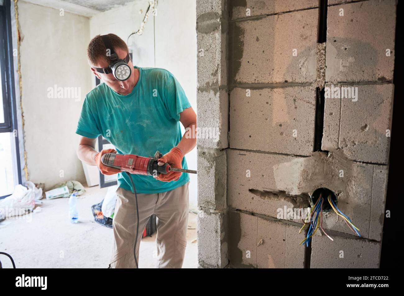 Male construction worker drilling brick wall with electric drill in ...