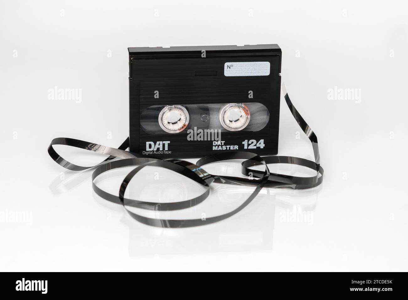 A DAT (Digital Audio Tape) cassette with twisted tape stands upright on ...