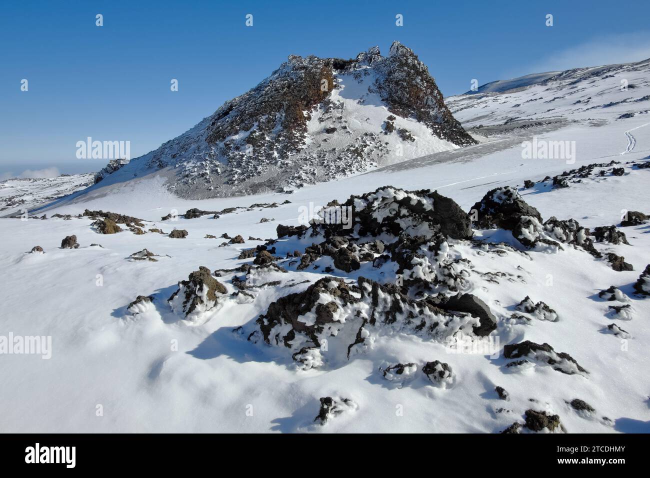 snowy lava field with volcanic rocks and hornito on mountainside of ...