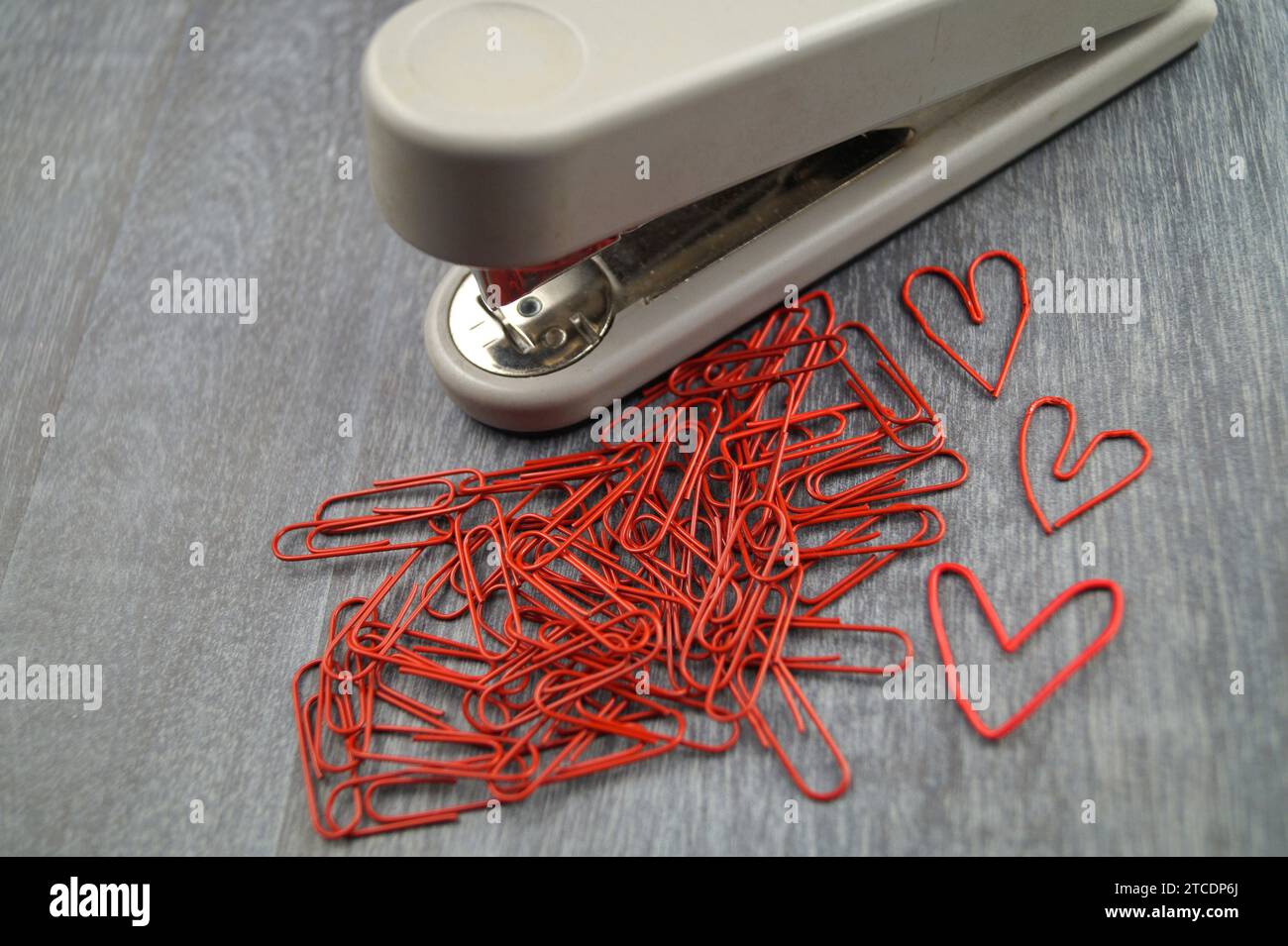 stapler with red paper-clips, three of them heart-shaped, love in the ...