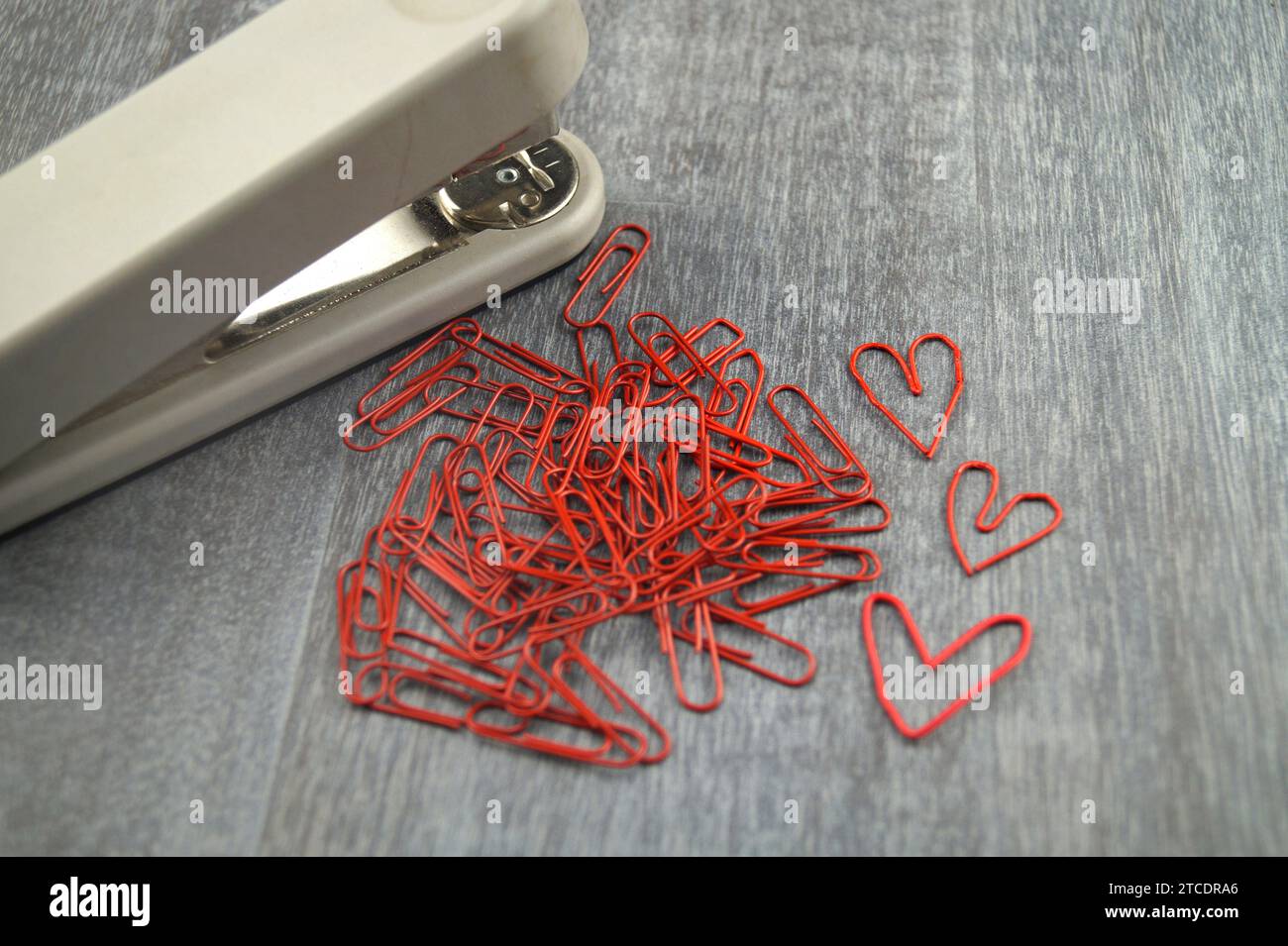 stapler with red paper-clips, three of them heart-shaped, love in the ...
