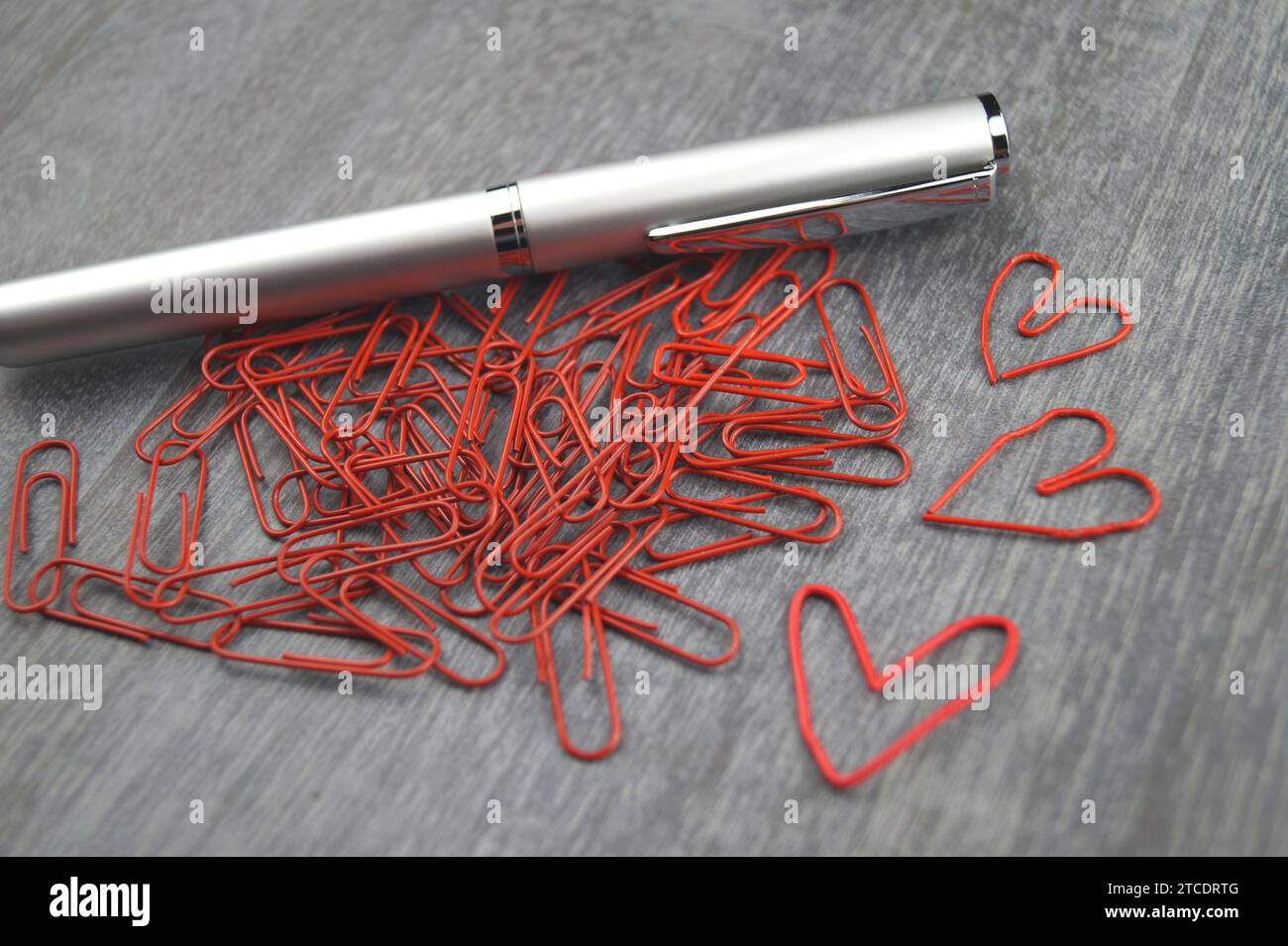 pen and red paper-clips, three of them heart-shaped, love in the office ...