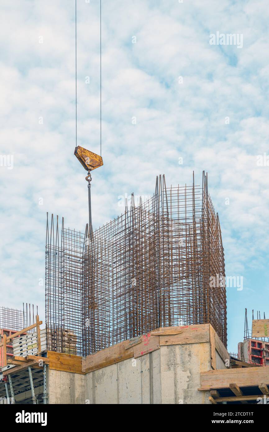 Construction crane hook lifting steel bars on building site, low angle ...