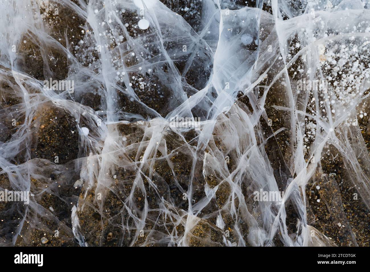 Cracks on surface of lake create ice pattern. Methane bubbles in Baikal ...