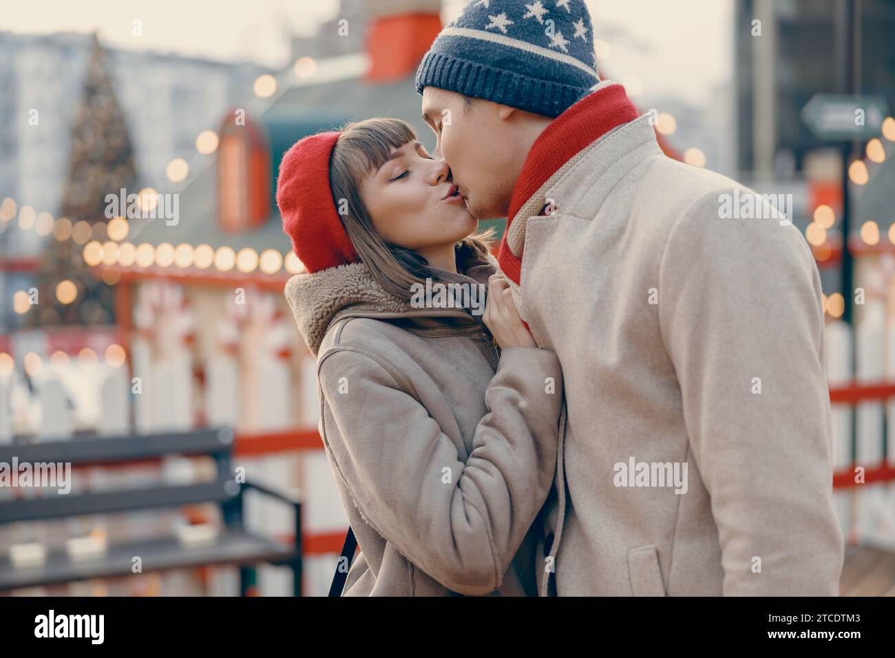 Romantic couple kissing gently at a festive outdoor Christmas market ...