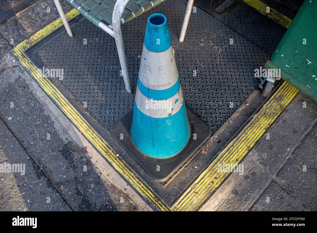An orange traffic cone located in the center of a busy sidewalk in an ...