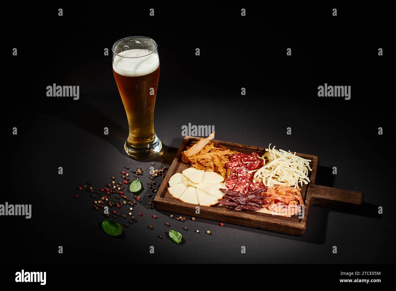 glass of cold beer near charcuterie board with gourmet cheese, dried ...