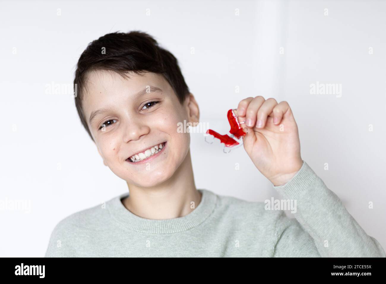 Boy smiling with tooth retainers in hand. Concept of crooked teeth ...