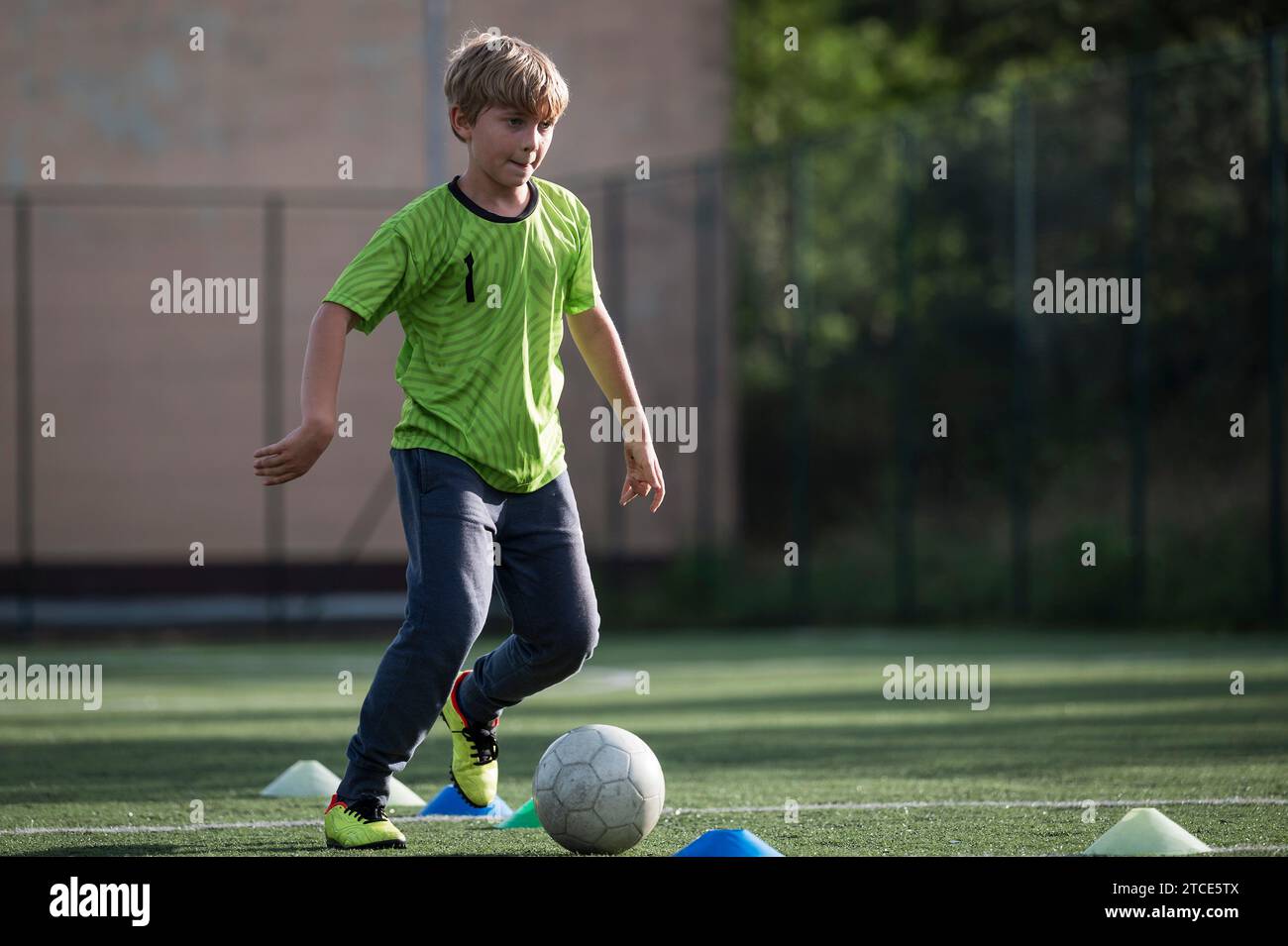 Young boy trains football at the pitch Stock Photo - Alamy