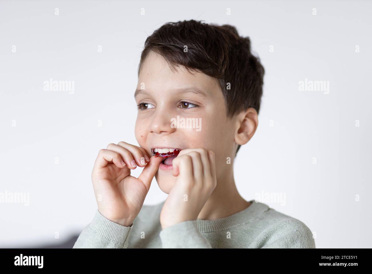 A boy puts on retainers, on a white background. Concept of correcting ...