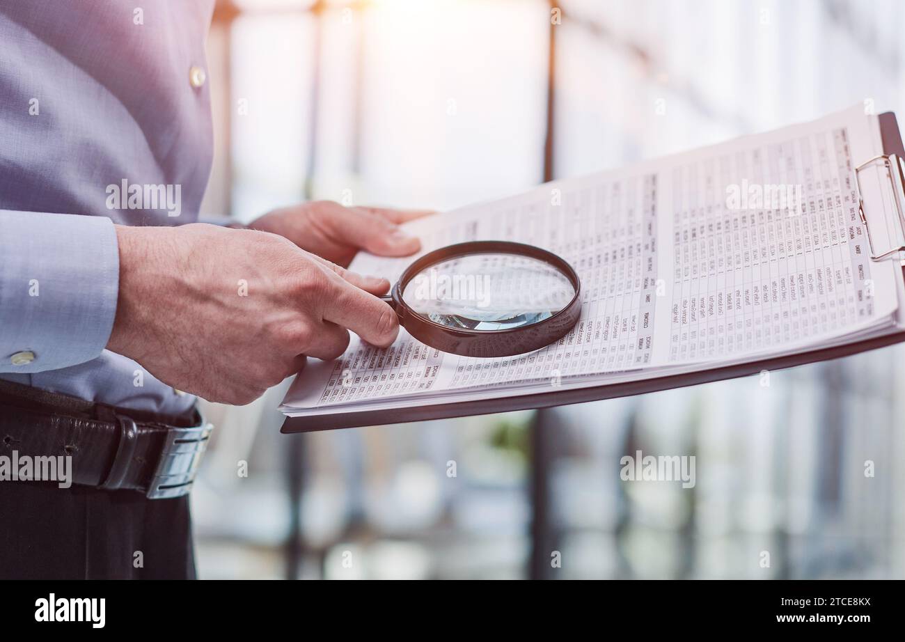 Businessman looking through a magnifying glass to documents Stock Photo ...