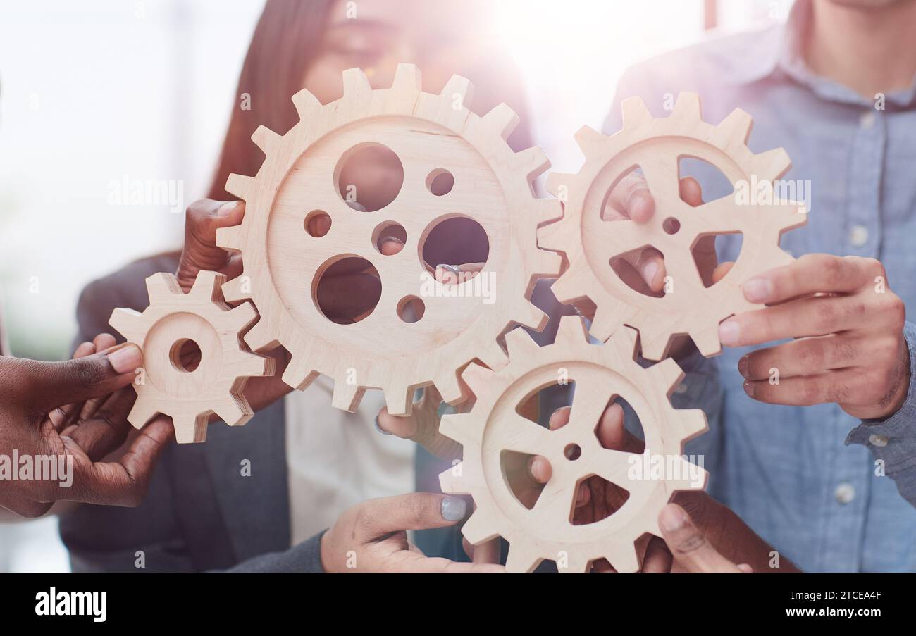 Office worker holding cog wheel as unity and teamwork in corporate ...