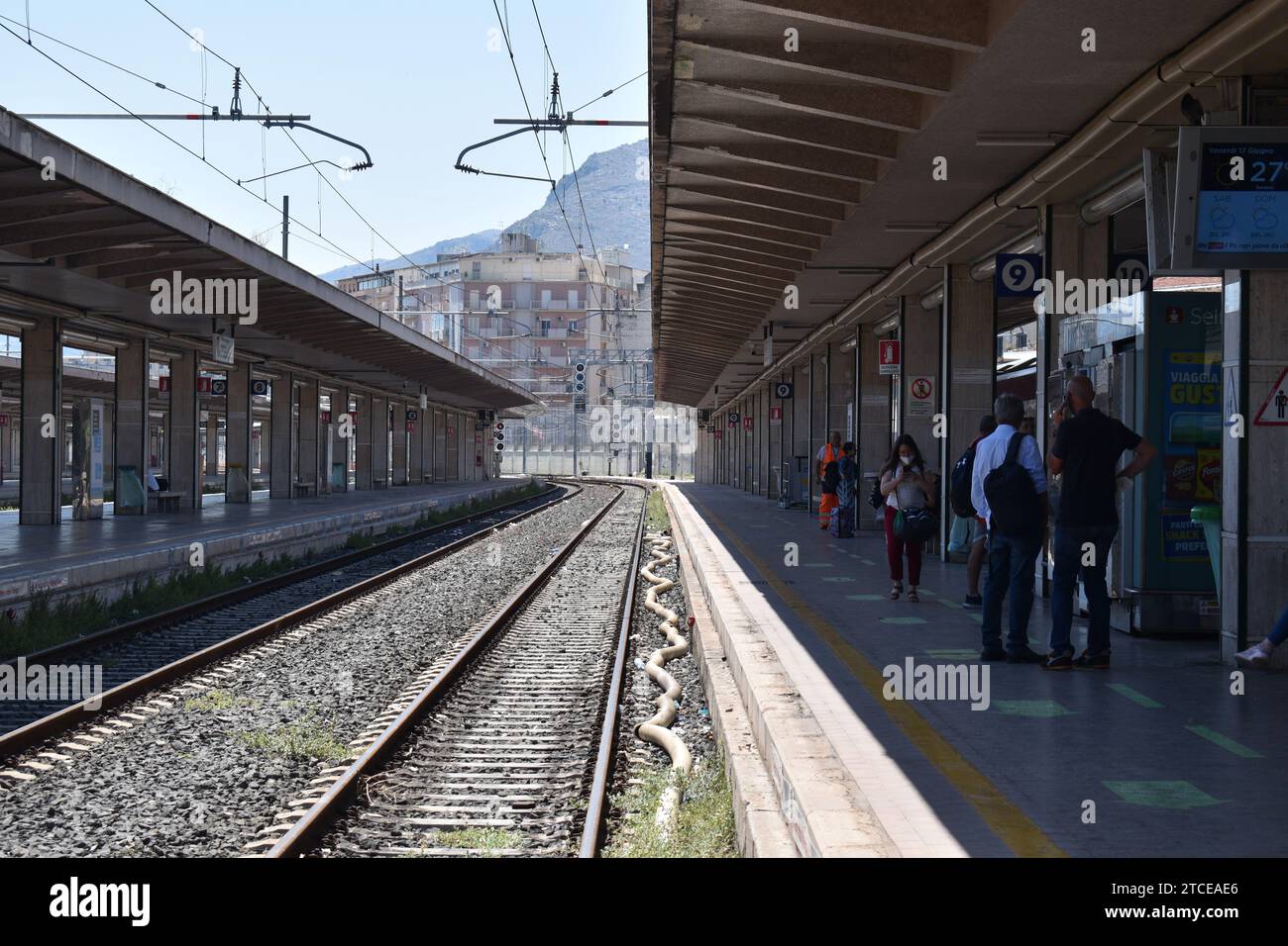 People walking on the train platform next to the empty rail tracks in Palermo Central Station ...
