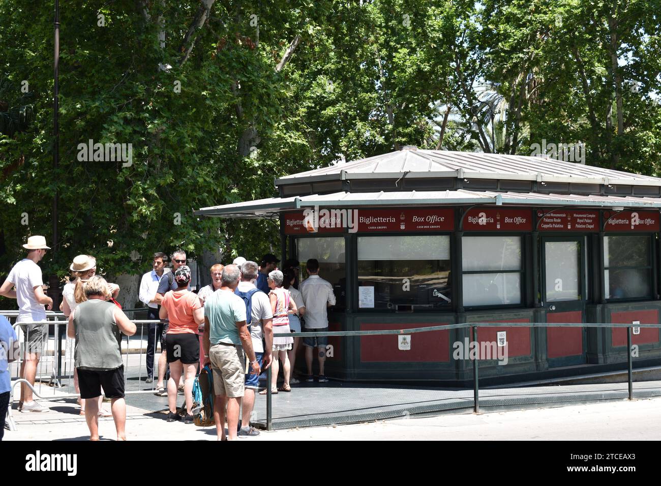 People standing in line in the sun at the ticket office to buy a ticket ...