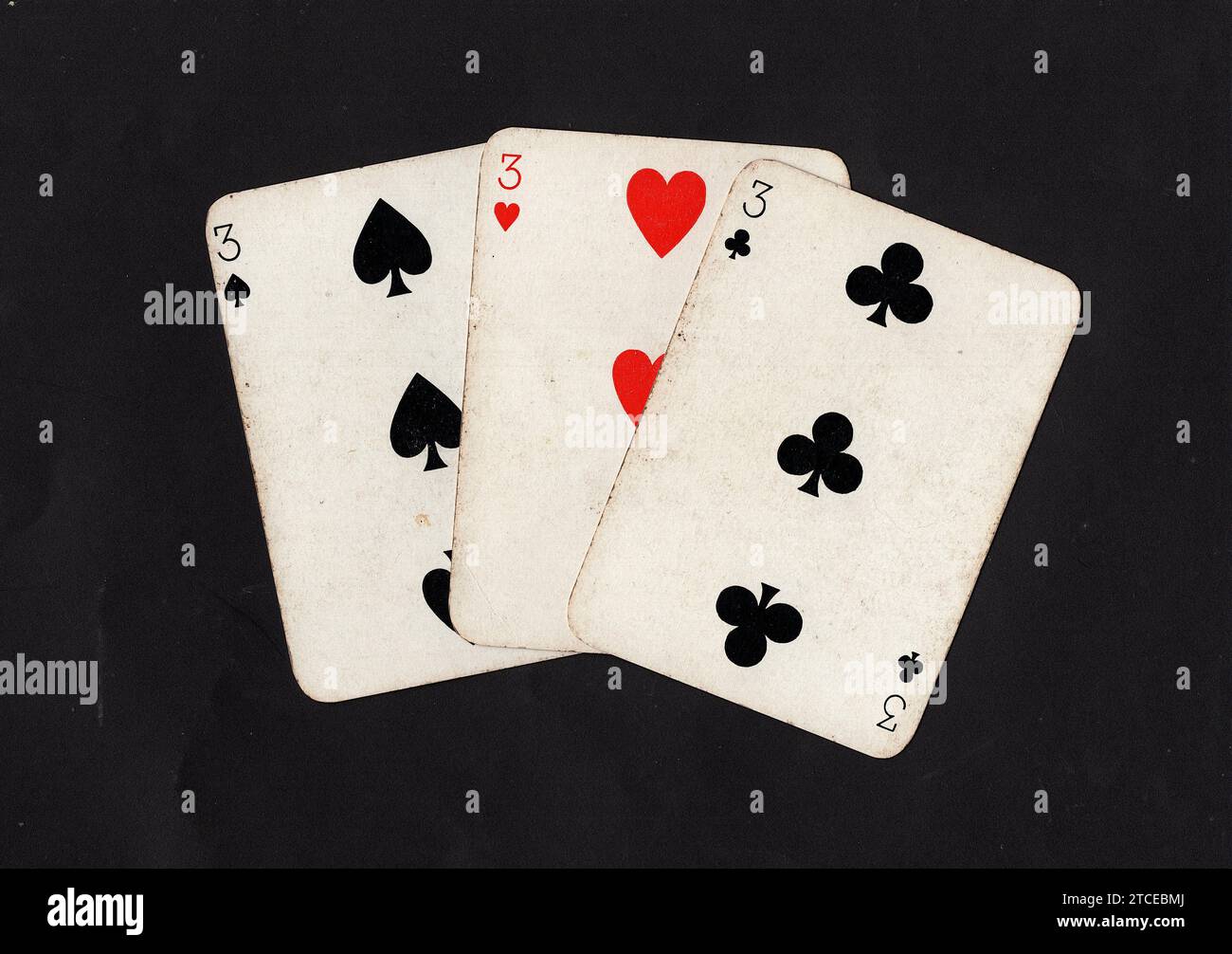 A hand of vintage playing cards showing three threes isolated on a ...