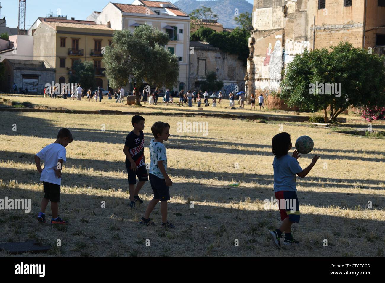 Four Sicilian boys playing with a soccer ball in the shadow at Piazza ...