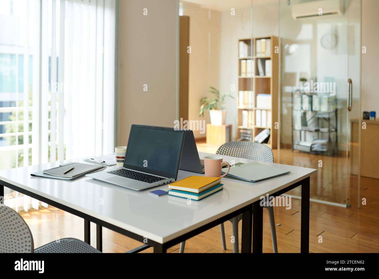 Desks with laptops, documents and planners in office of small company ...