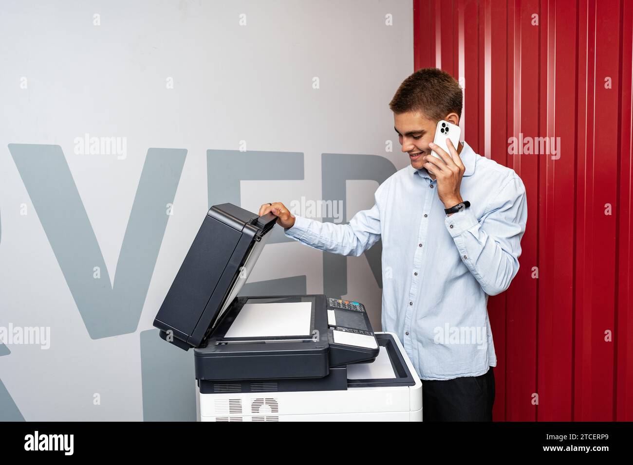 Positive young man using printer in the modern office Stock Photo - Alamy