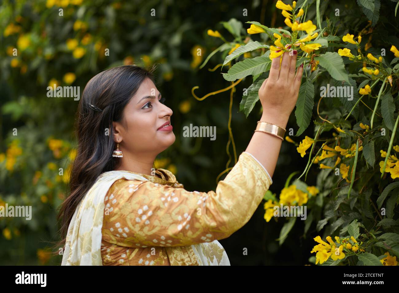 Indian woman in traditional dress enjoying beauty of blooming flowers ...
