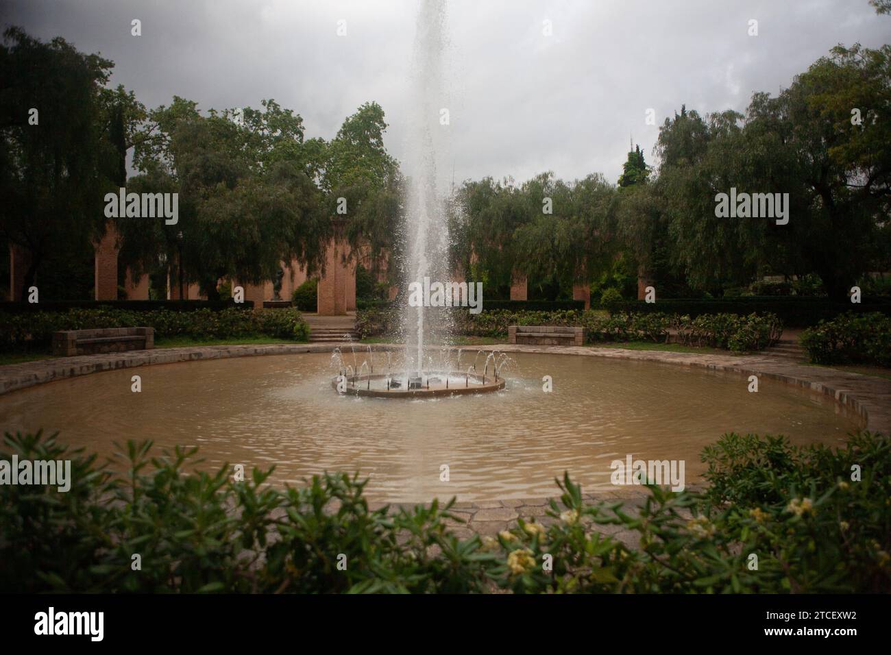 A circular fountain is the centerpiece of a serene, landscaped area ...