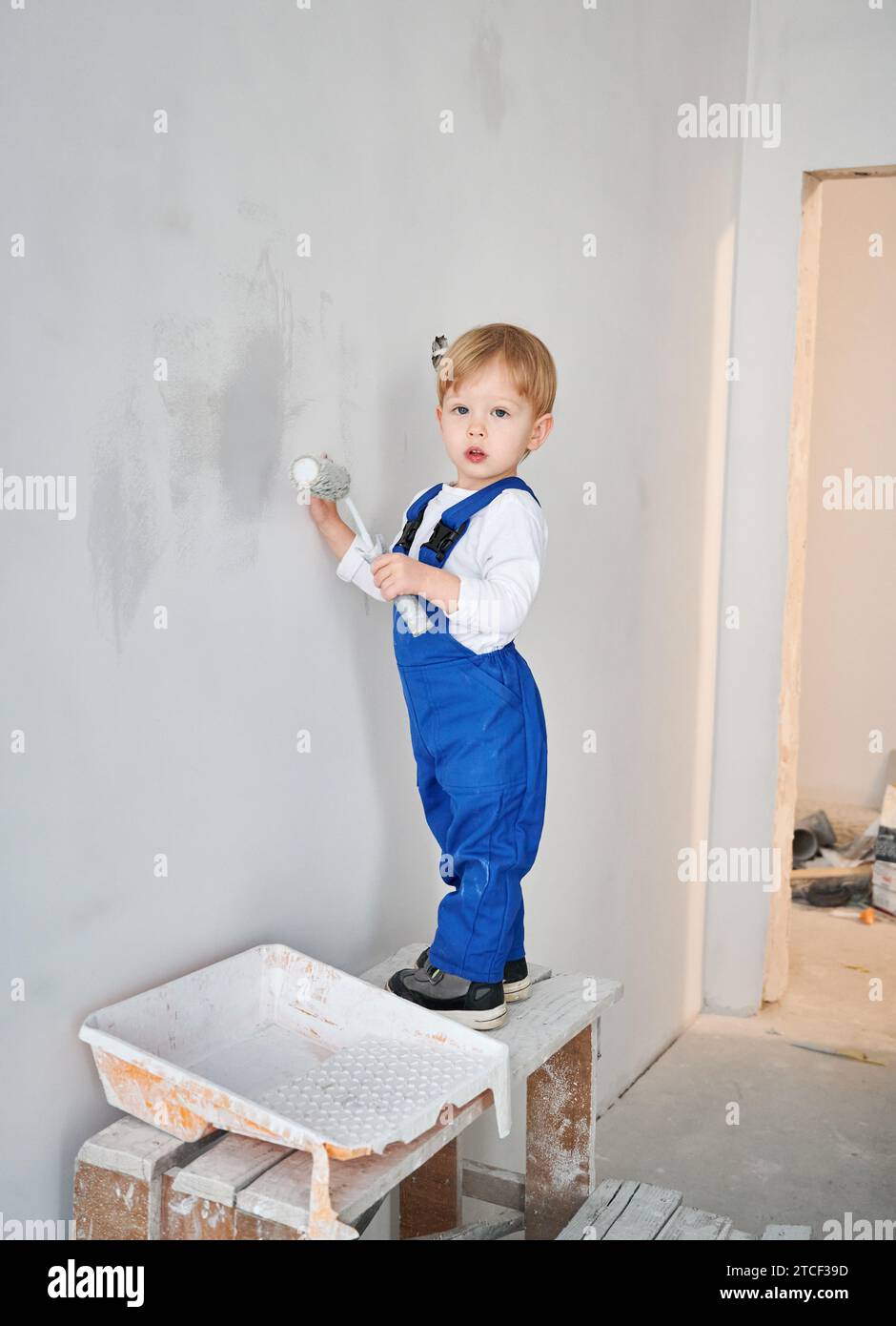 Little boy construction worker painting wall in apartment under ...