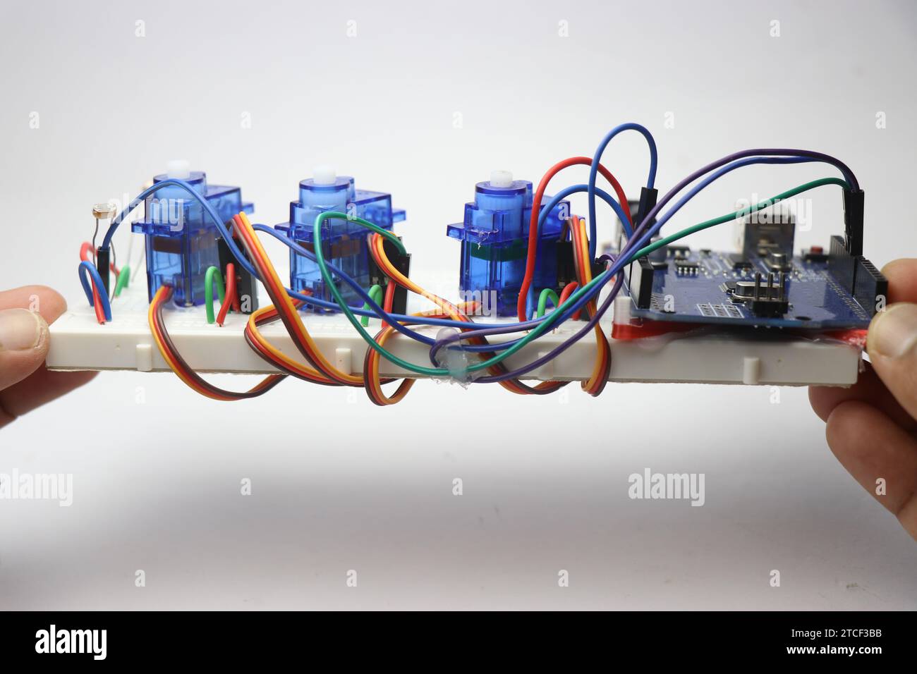 Micro servos of plastic geared type on a breadboard connected to ...