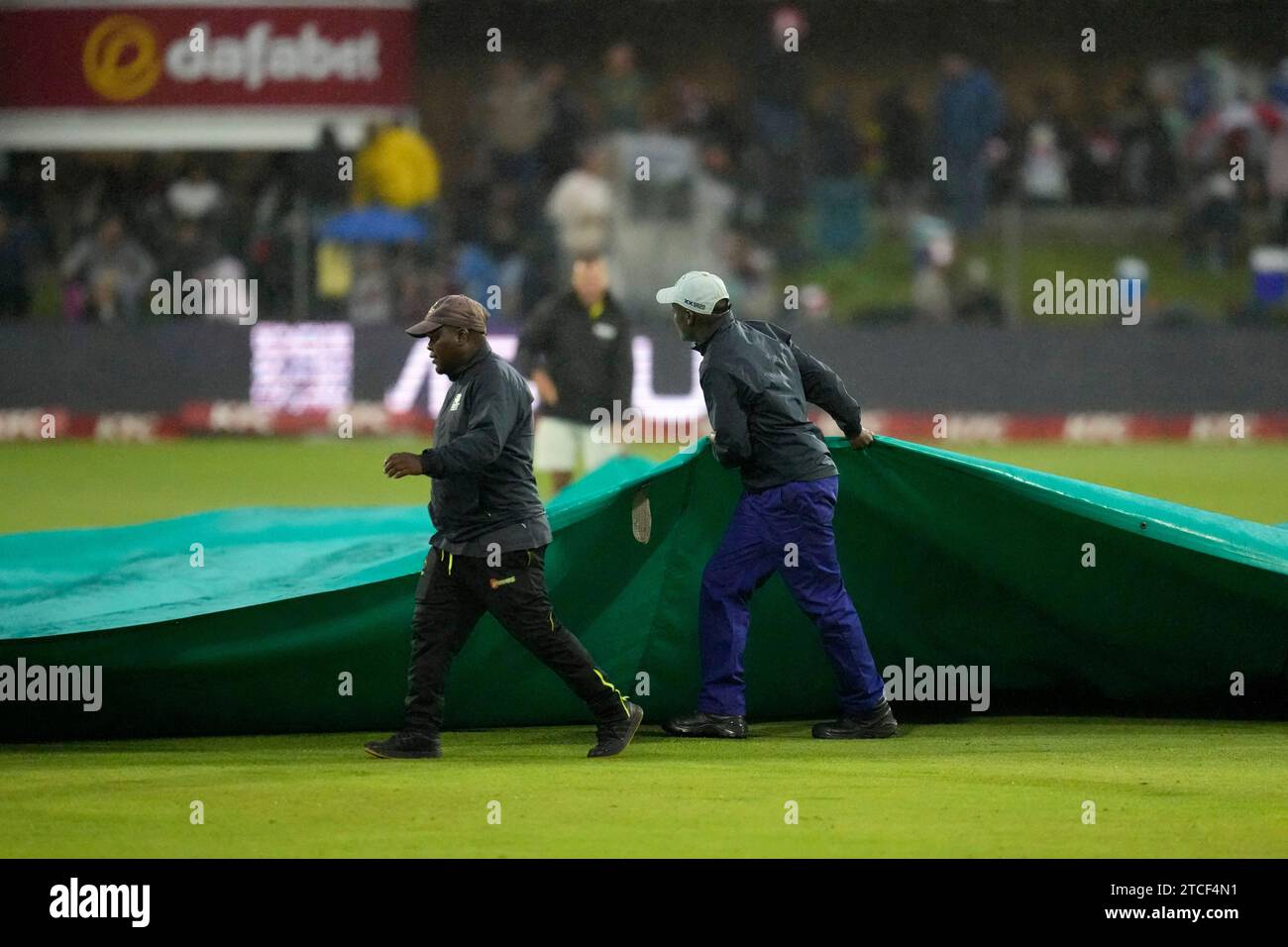 Ground workers pull rain covers as play is delayed during the second ...