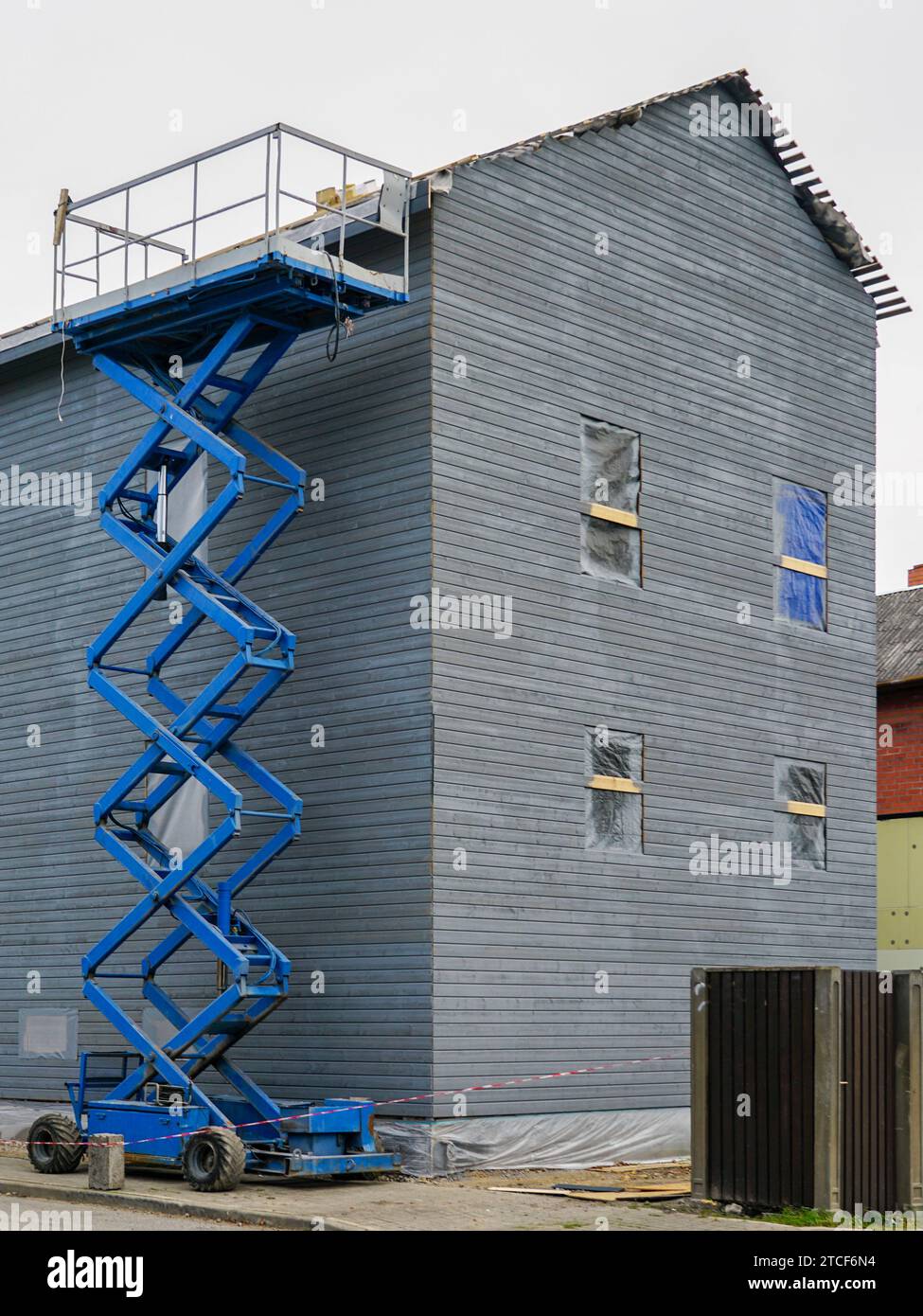 A blue mobile scissor lift platform high elevated next to the grey ...