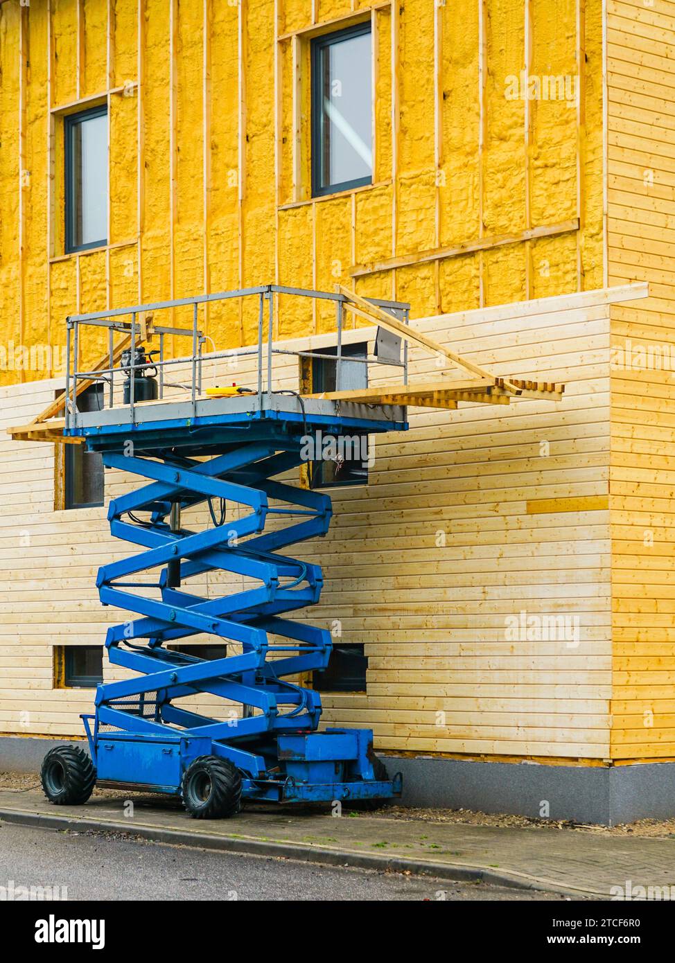 Using a scissor lift in facade cladding works after spraying the facade ...