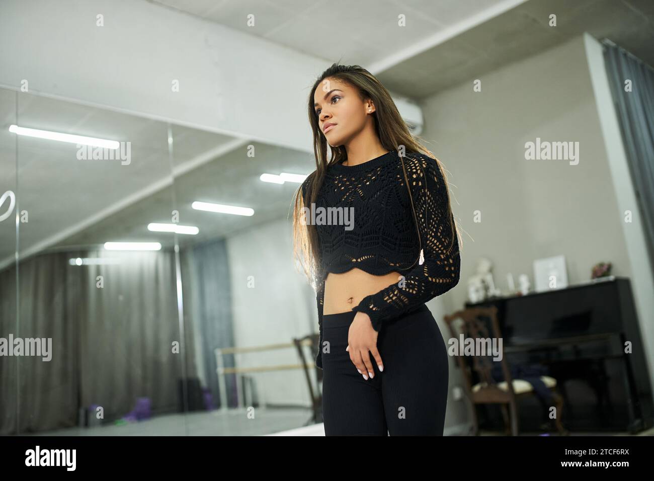 talented dark-skinned woman in black attire rehearsing dance in studio ...