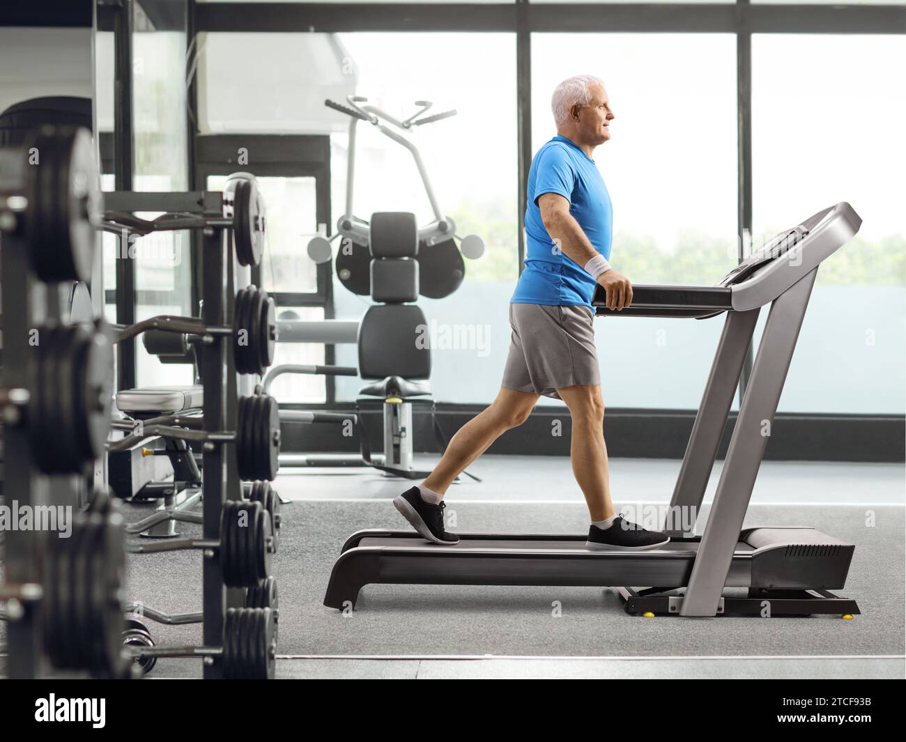 Full length profile shot of a mature man walking on a treadmill at the ...