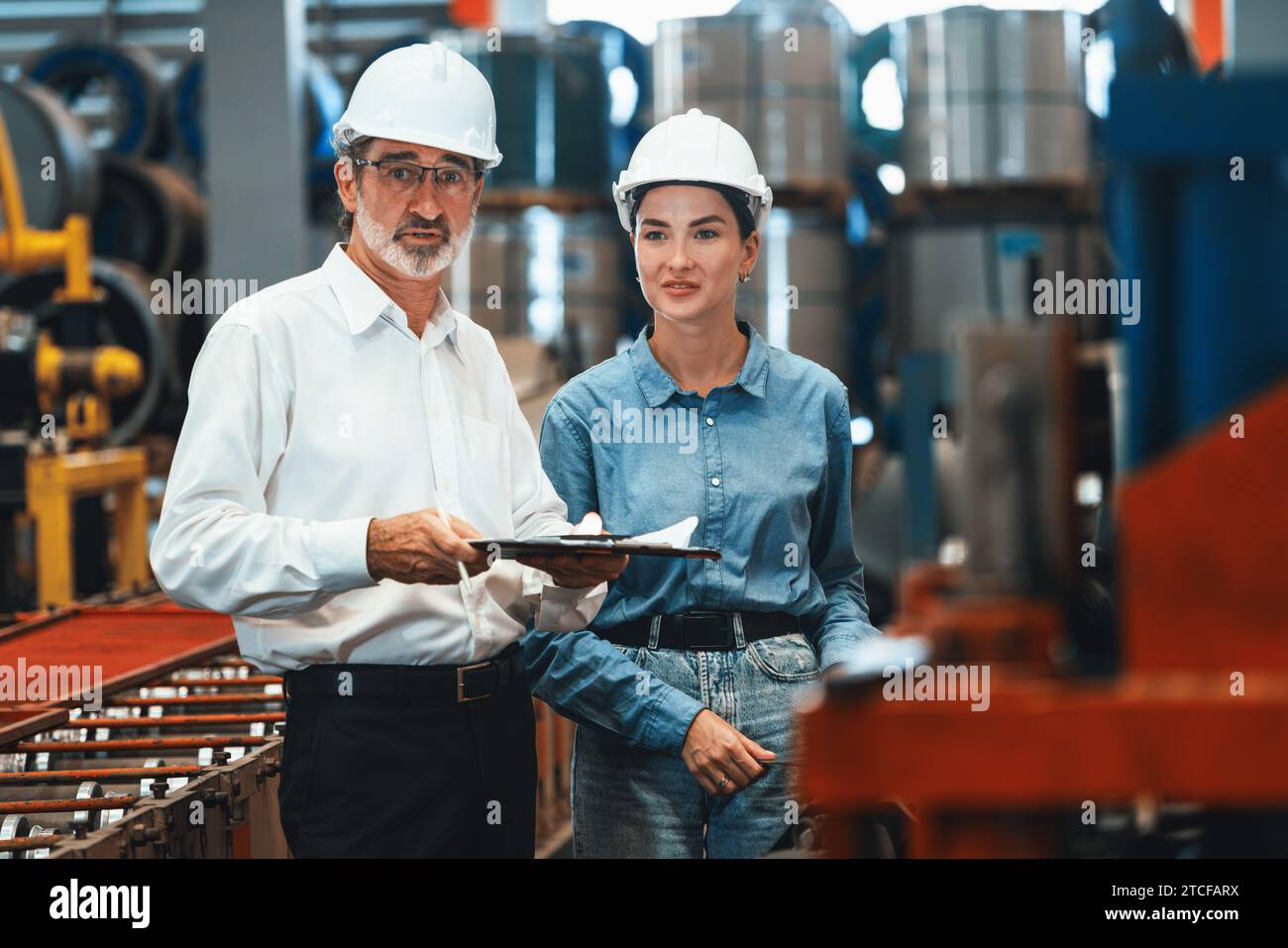 Factory engineer manager with assistant using laptop to conduct ...