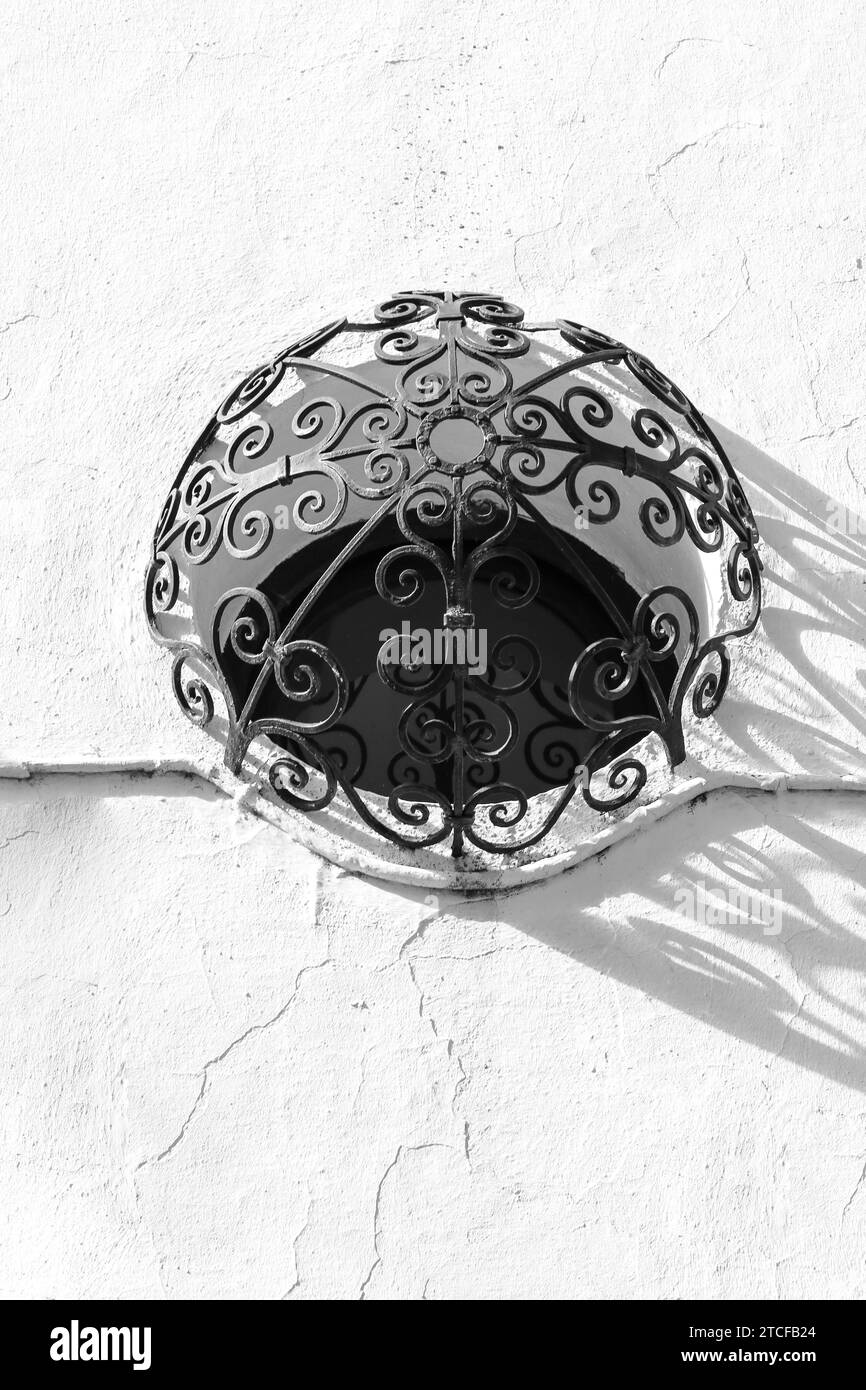 Round window with wrought iron lattice on whitewashed facade in Ronda ...