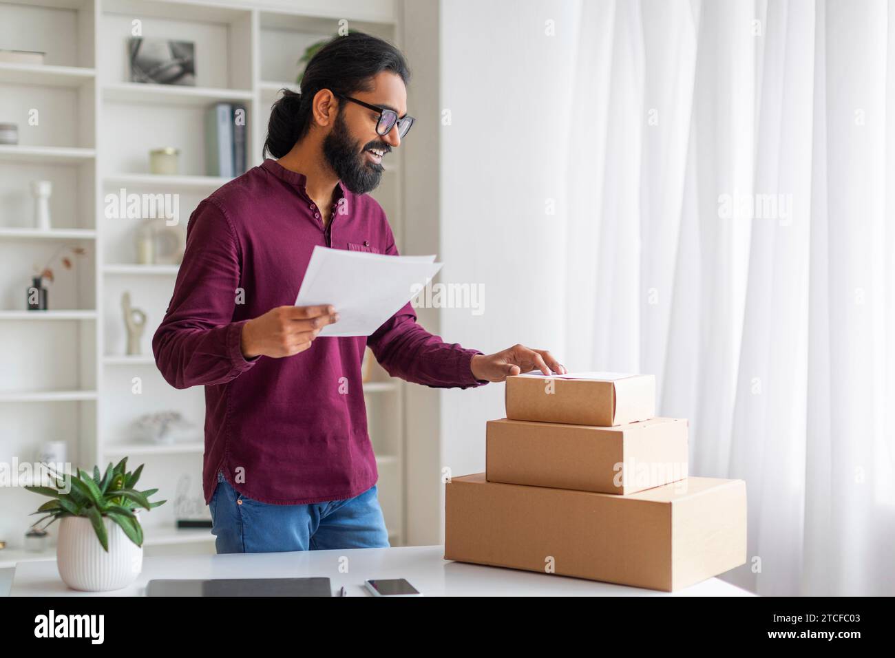 Focused Indian businessman reviewing documents and organizing shipping ...