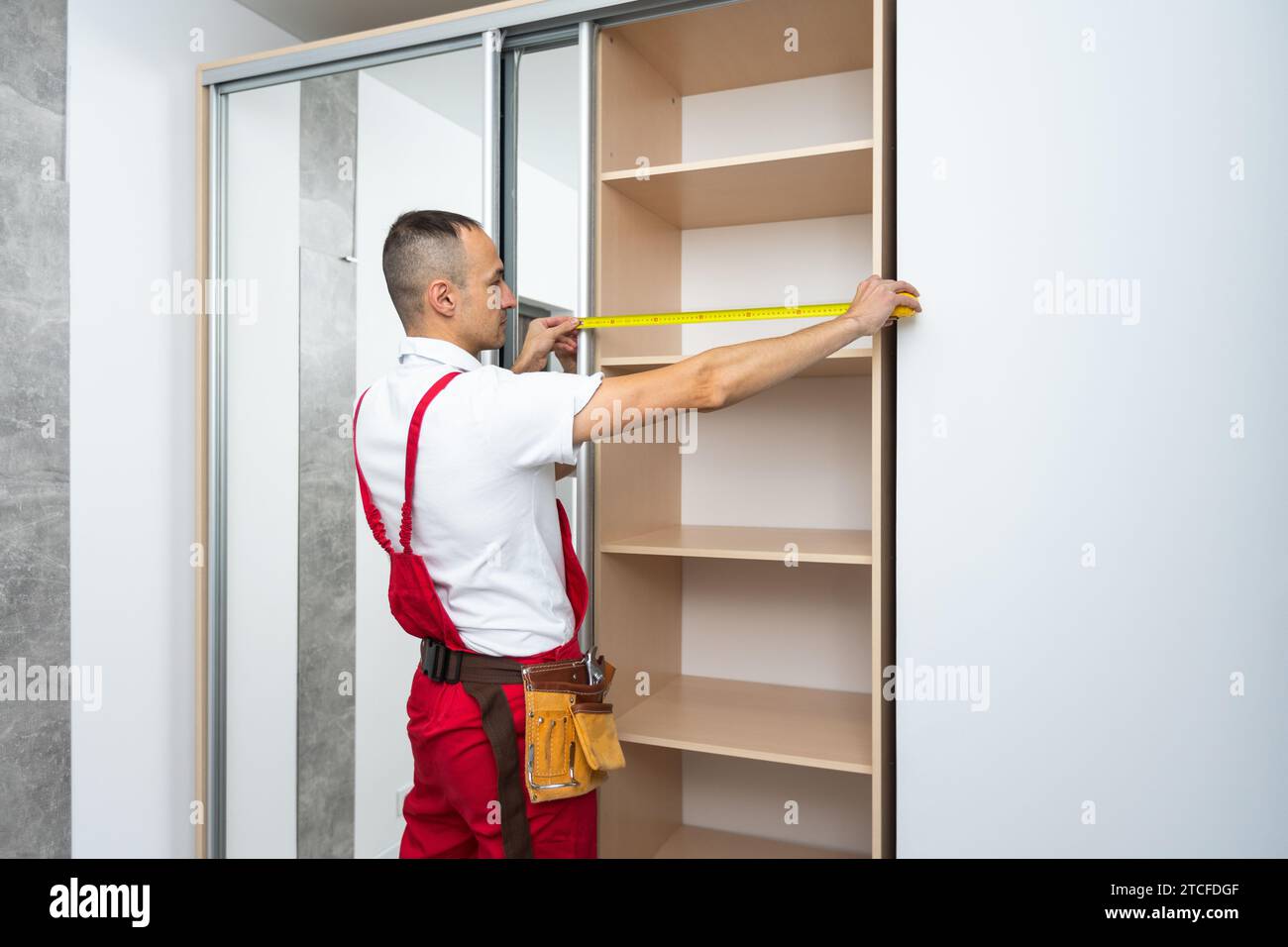 Furniture assembling. Professional worker installing wardrobe at living ...