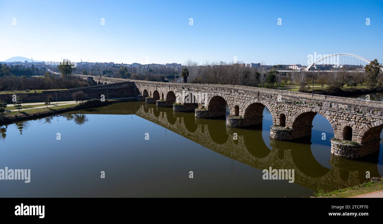 The ancient Roman stone bridge with arches reflecting in calm water and ...