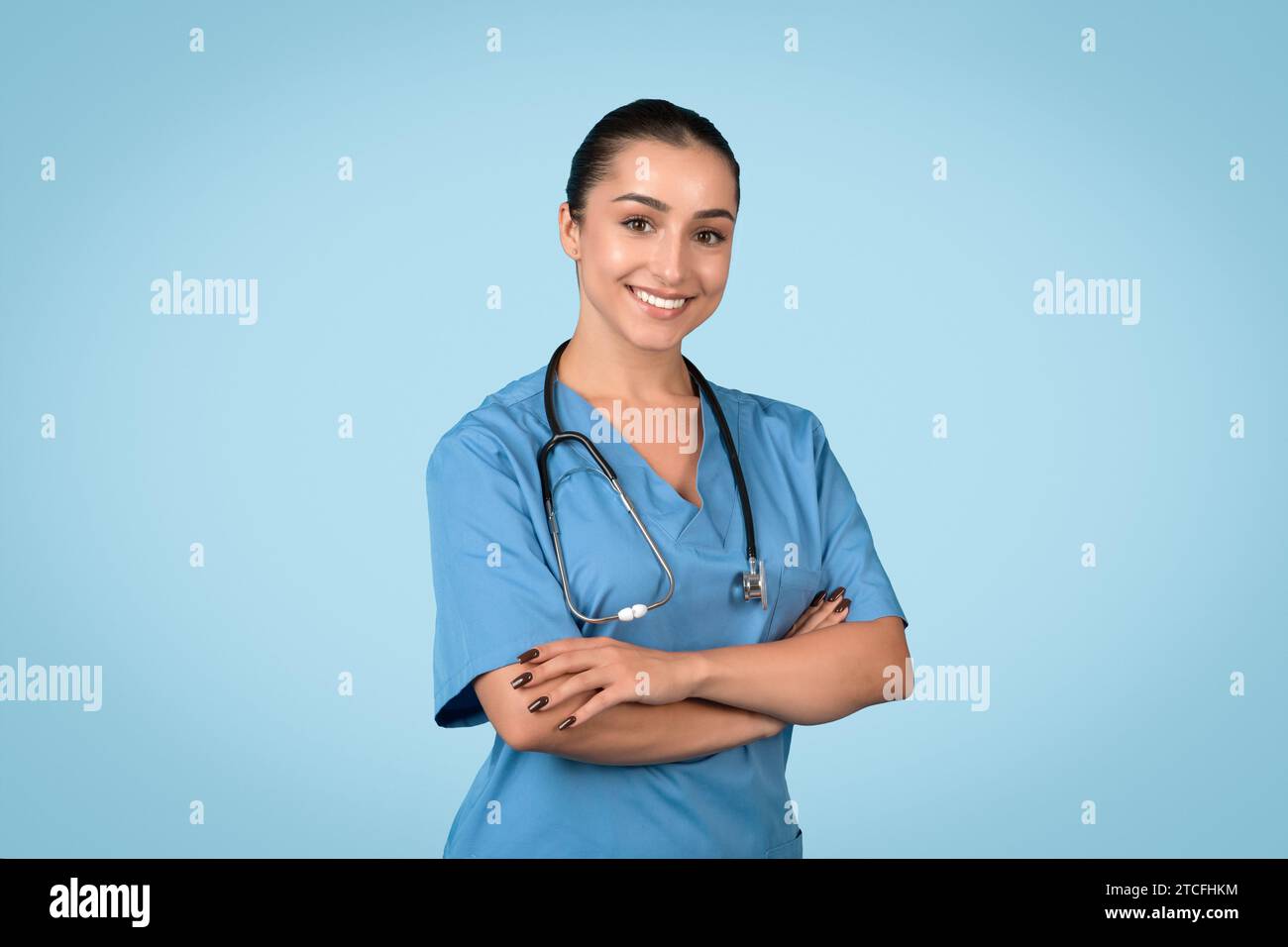 Confident female nurse in blue scrubs with arms crossed Stock Photo - Alamy