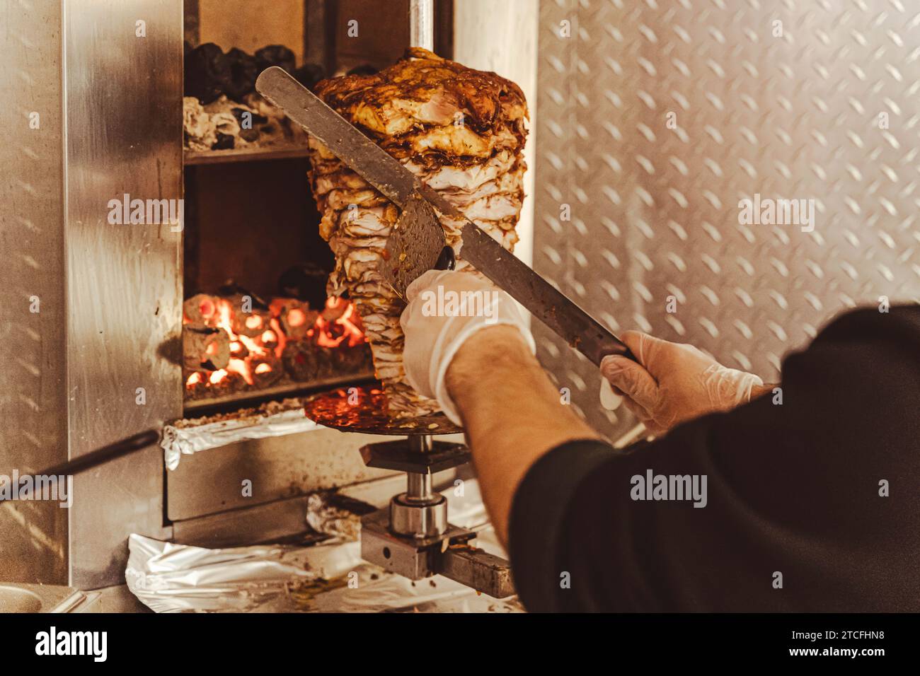 A skilled chef cuts pieces of meat from a rotating shish kebab skewer ...