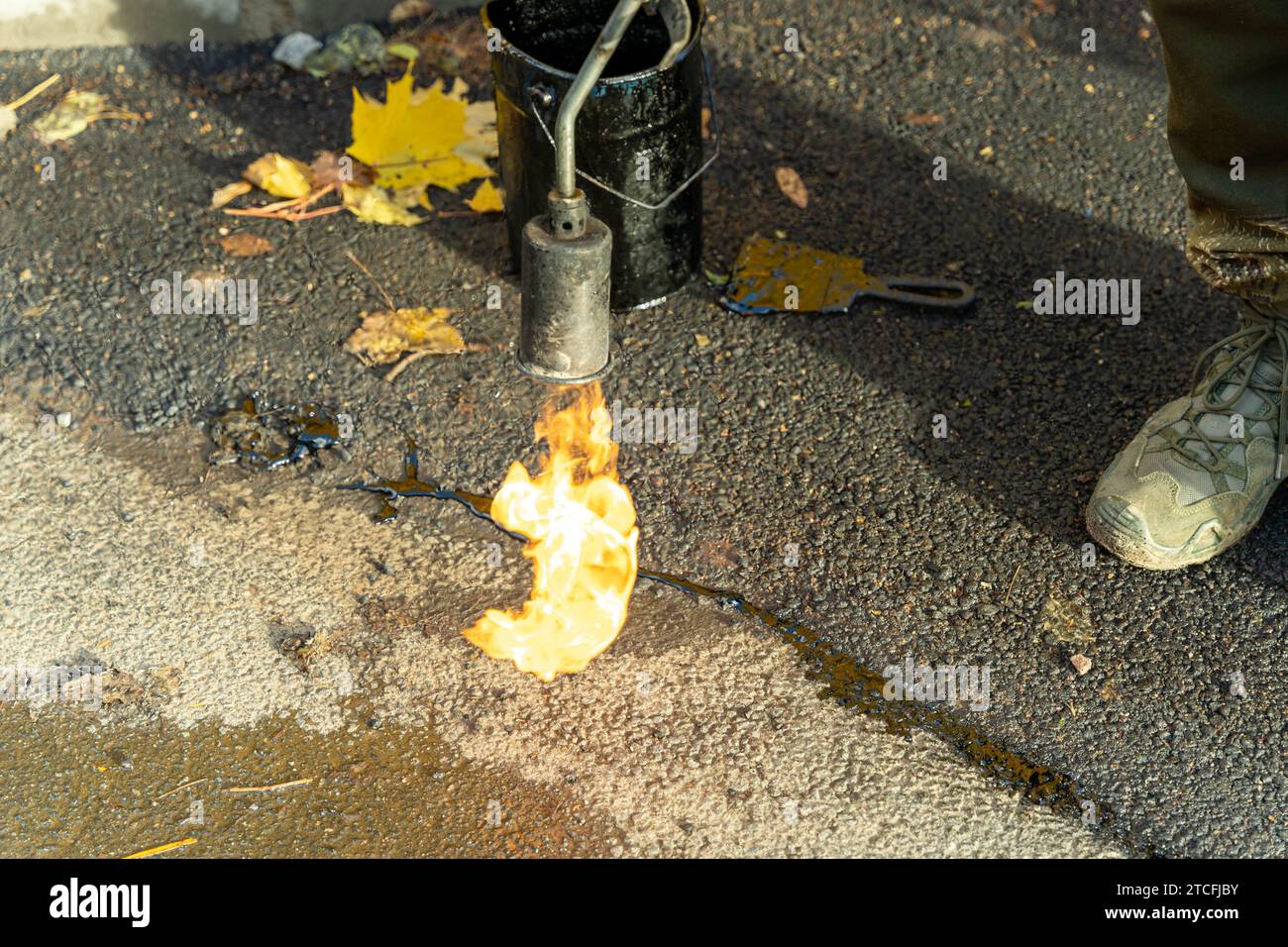 Professional maintenance of asphalt cracks using mastic and a gas ...