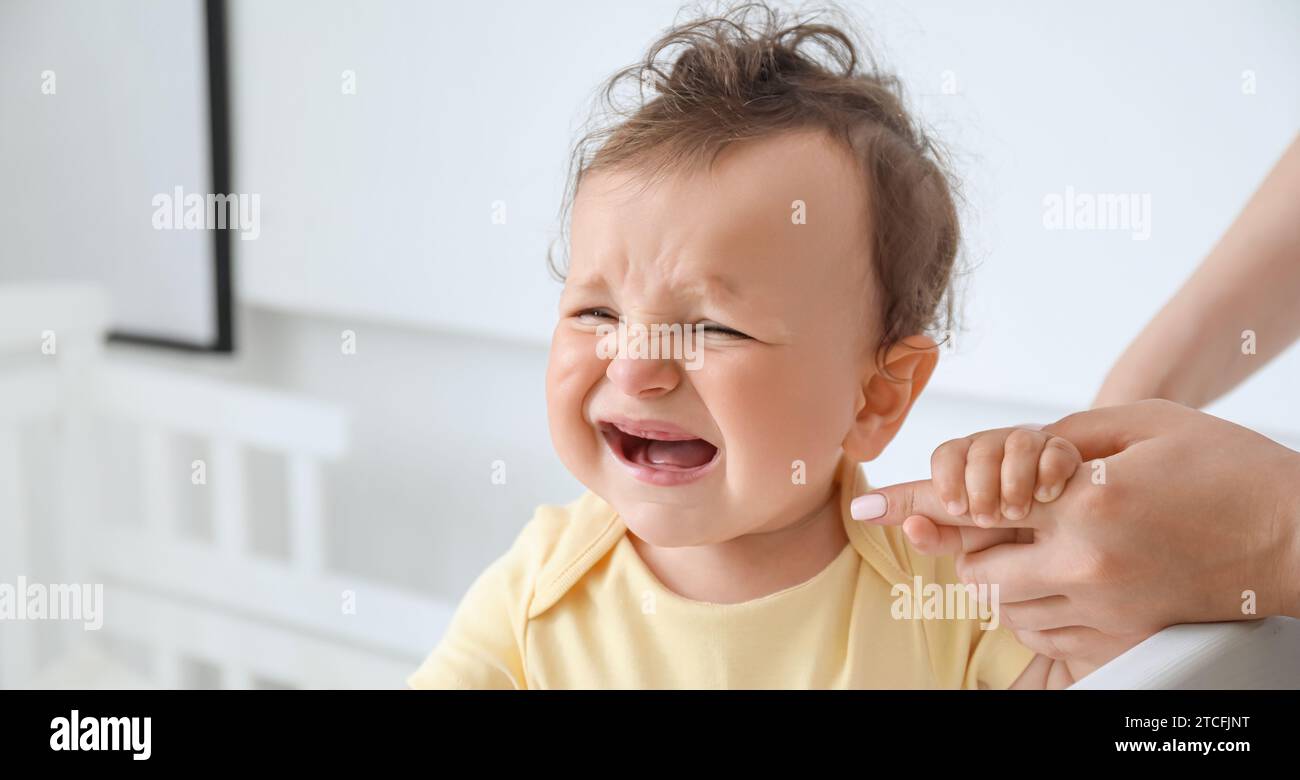Crying little baby with mother in crib Stock Photo - Alamy