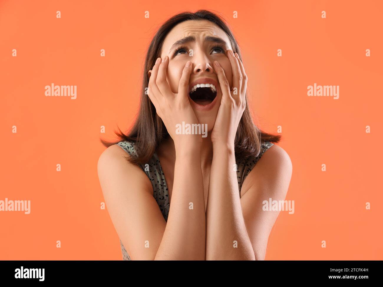 Beautiful young afraid woman screaming on orange background Stock Photo ...
