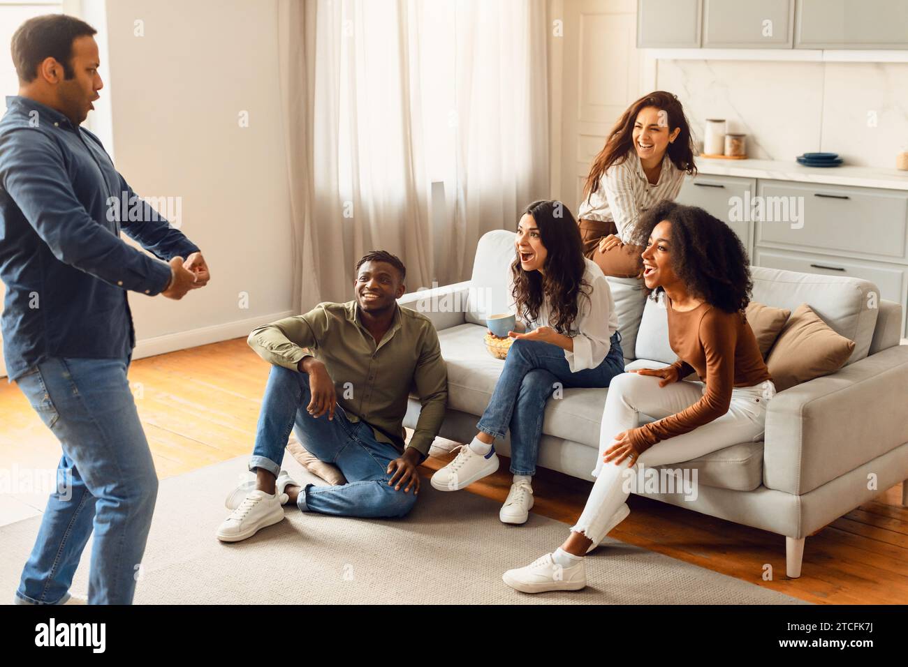Multiracial young friends playing charades game having fun at home ...