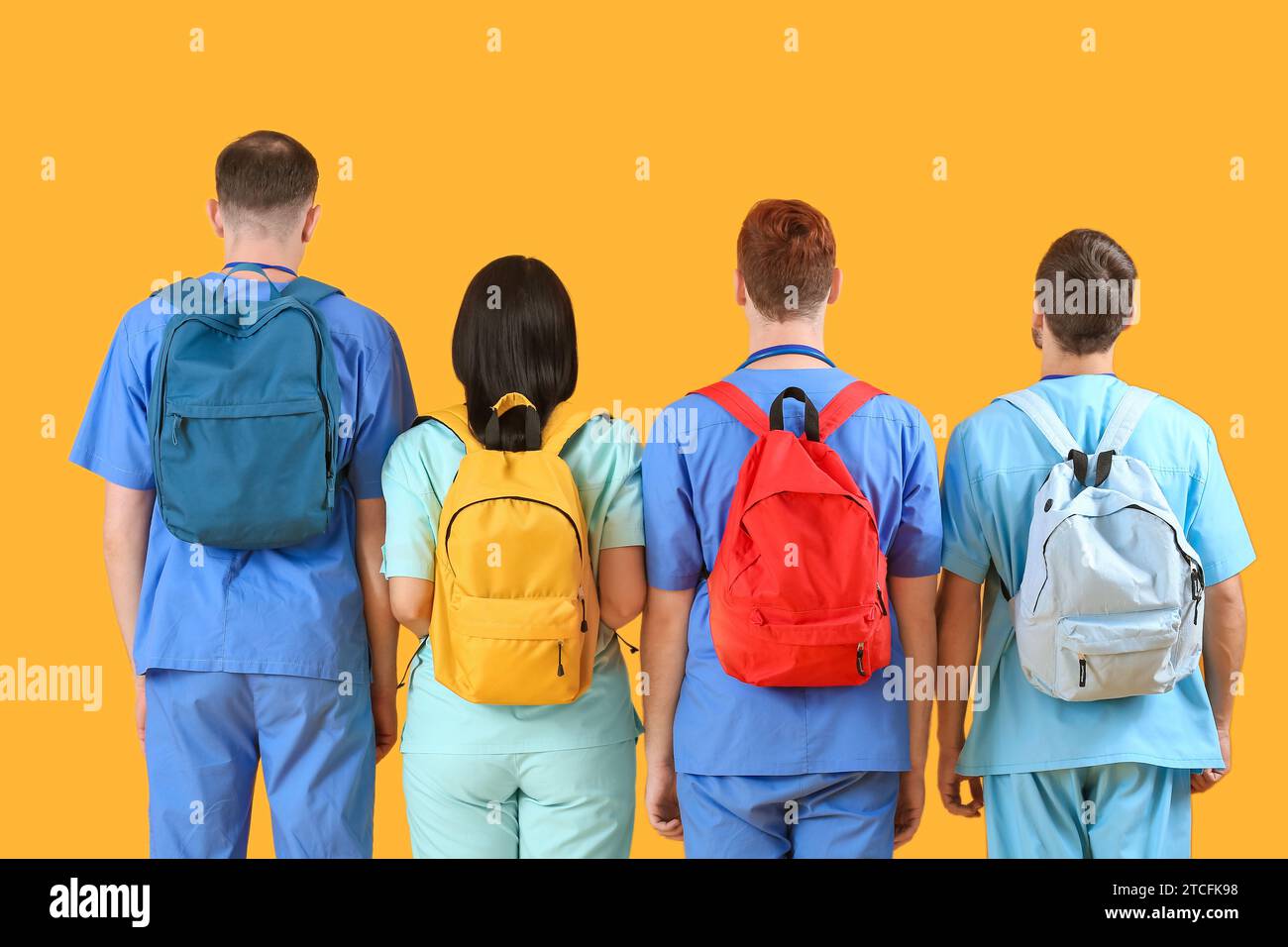 Group of medical students with backpacks on yellow background, back ...