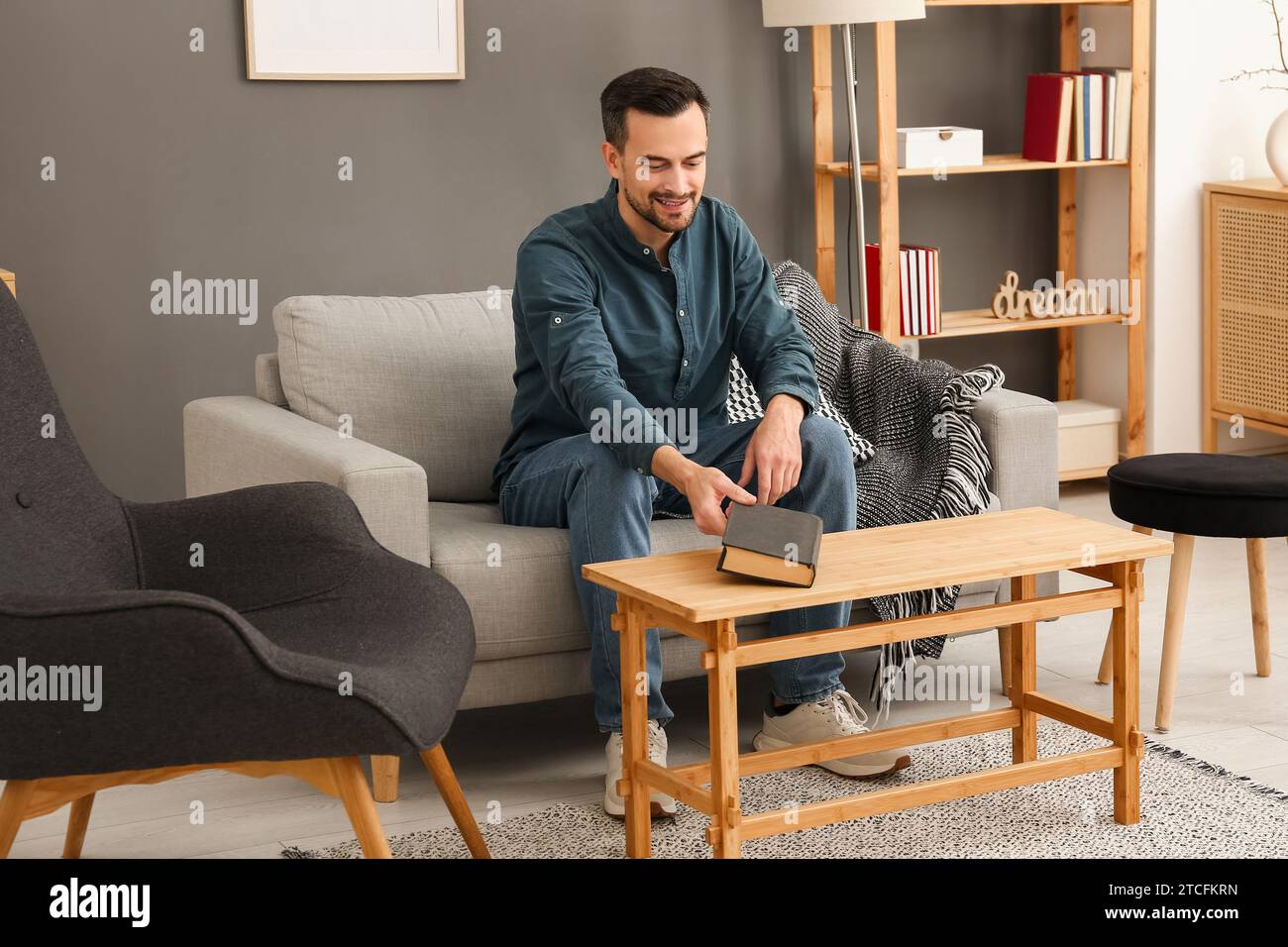 Handsome man taking book from table at home Stock Photo - Alamy