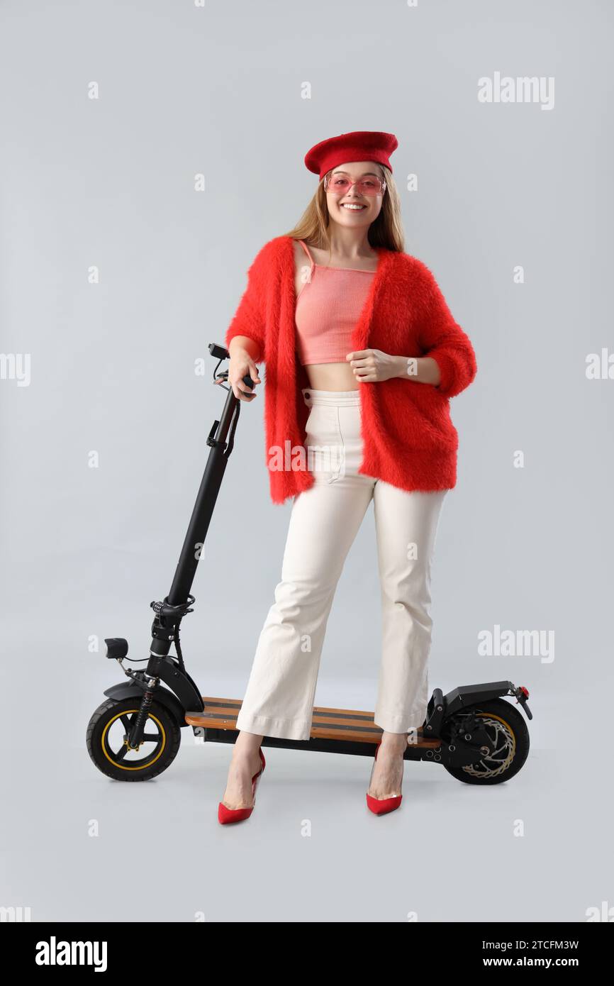 Stylish young woman with electric scooter on light background Stock ...